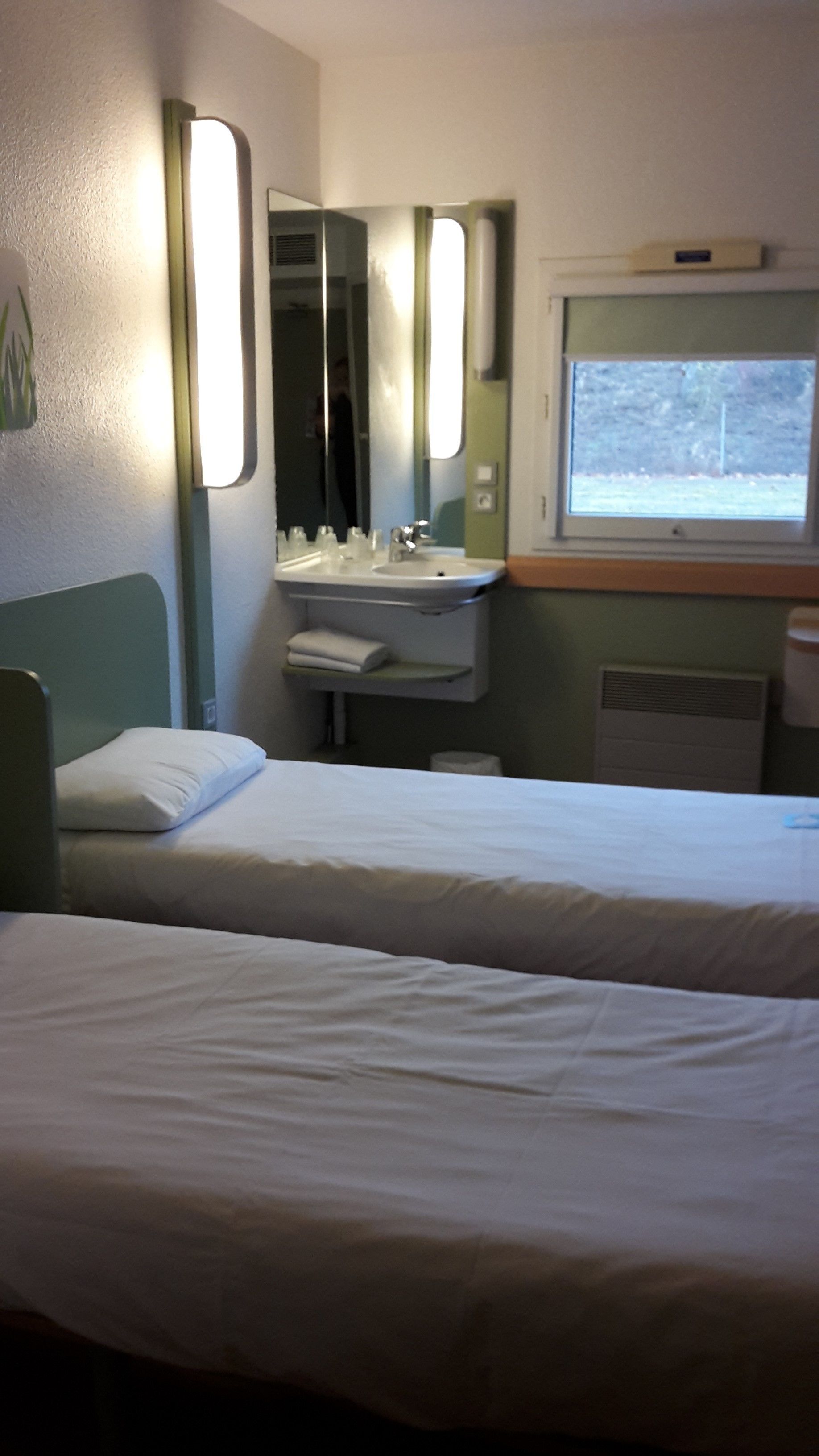 Quarto de hotel com duas camas, pia e janela.
