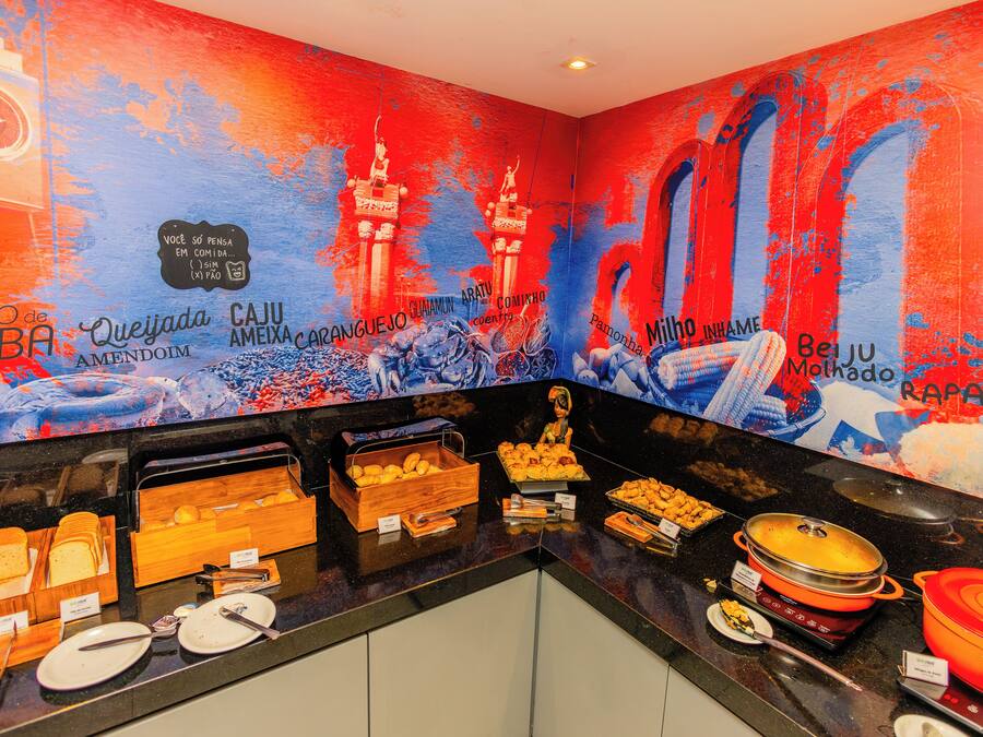 Uma área de buffet com diversos alimentos e um mural colorido ao fundo.