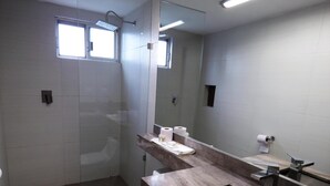 Uma casa de banho moderna com chuveiro, sanita e lavatório.