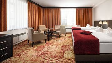 Quarto de hotel com duas camas, um sofá, uma mesa e uma escrivaninha.