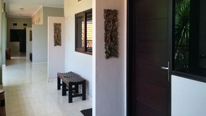 Um corredor com um banco, painéis decorativos na parede e uma porta grande com janela.