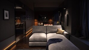 Uma sala de estar moderna com um sofá seccional, uma lareira e uma área de jantar visível através de um painel de vidro.