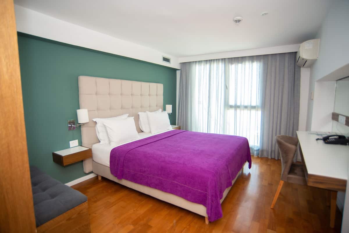 Quarto de hotel moderno com uma cama grande, uma mesa e uma cadeira.