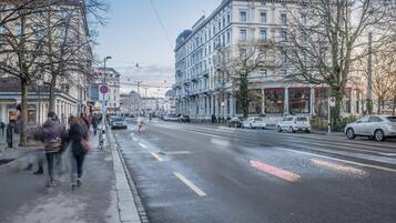 Uma rua com edifícios, carros e pedestres.
