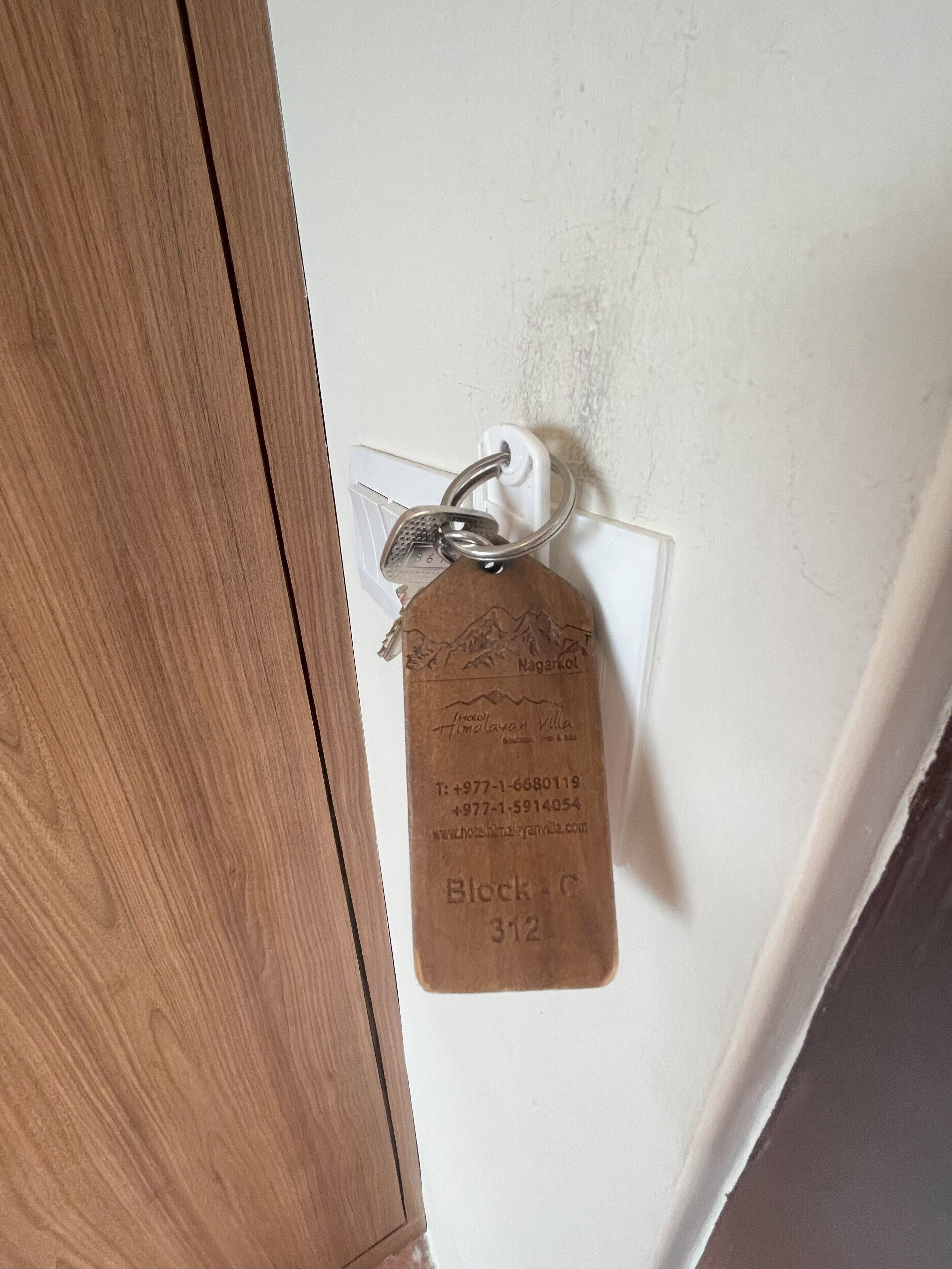 Uma porta de madeira com um chaveiro pendurado em uma parede branca.