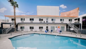 Um hotel moderno com piscina, várias varandas e um telhado laranja marcante.