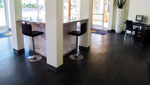 Uma área de recepção com dois bancos altos, uma mesa e um computador.