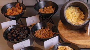 Buffet com diversas opções de comida, incluindo frutas, nozes e pão.