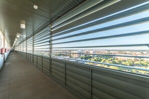 Um corredor com grades de metal e vista para a cidade através de grandes janelas.