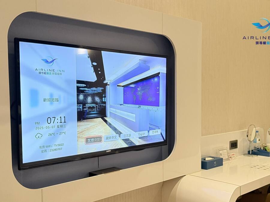 Mostrador digital num quarto de hotel a exibir a hora, data e temperatura.