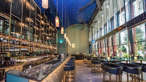 Um bar com um balcão comprido, vários bancos e uma variedade de garrafas.