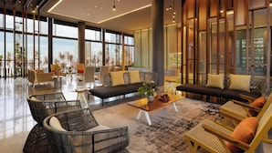 Um hall amplo com design moderno, apresentando uma grande área de estar com sofás e poltronas, uma mesa de centro e janelas amplas com vista para a cidade.