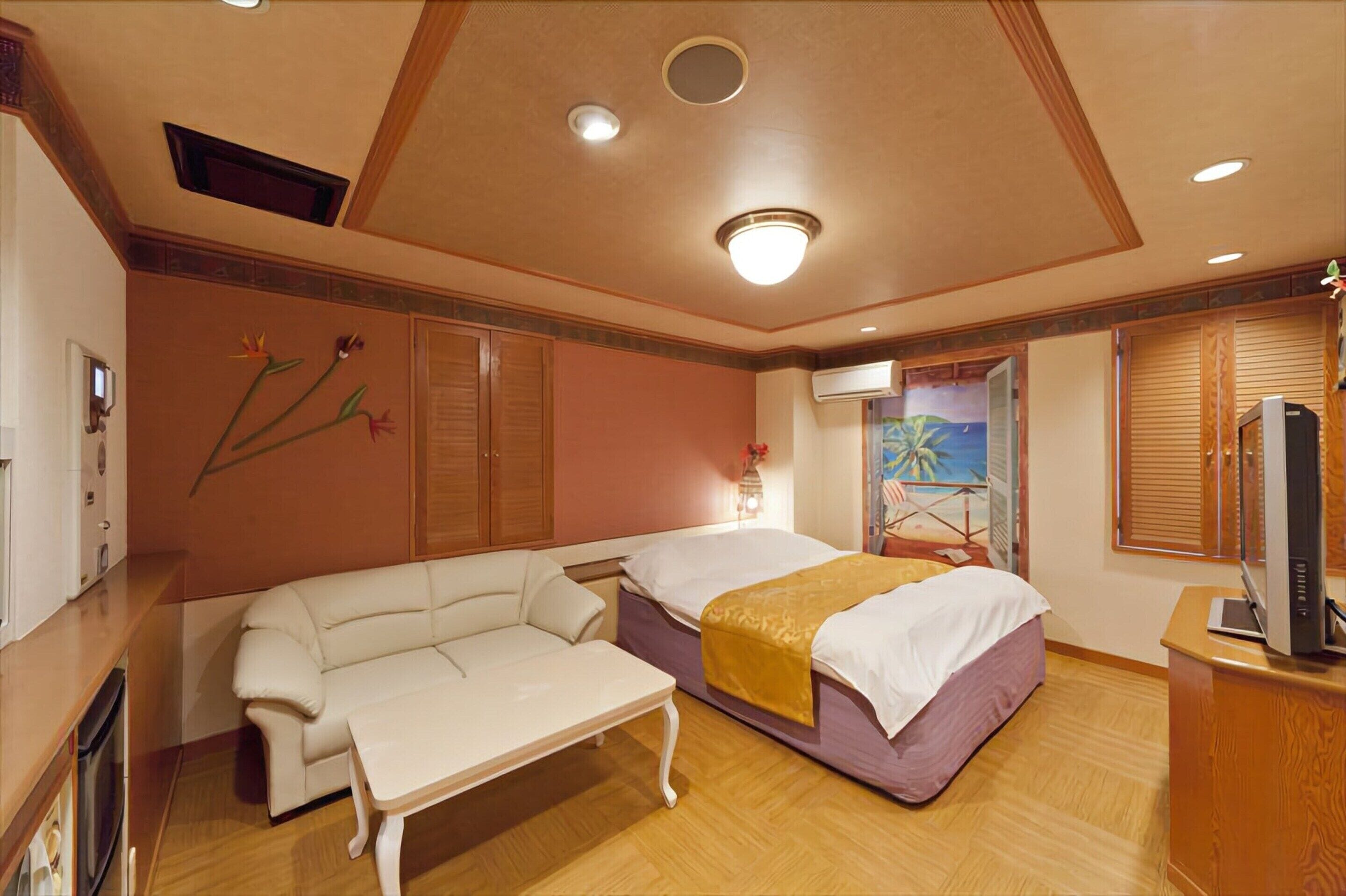 Quarto com cama, sofá, mesa de cabeceira, ar-condicionado e televisão.