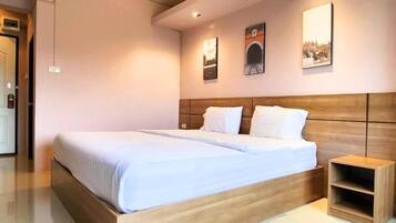 Quarto de hotel moderno com estrutura de cama de madeira, roupa de cama branca e uma pequena mesa de cabeceira de madeira.