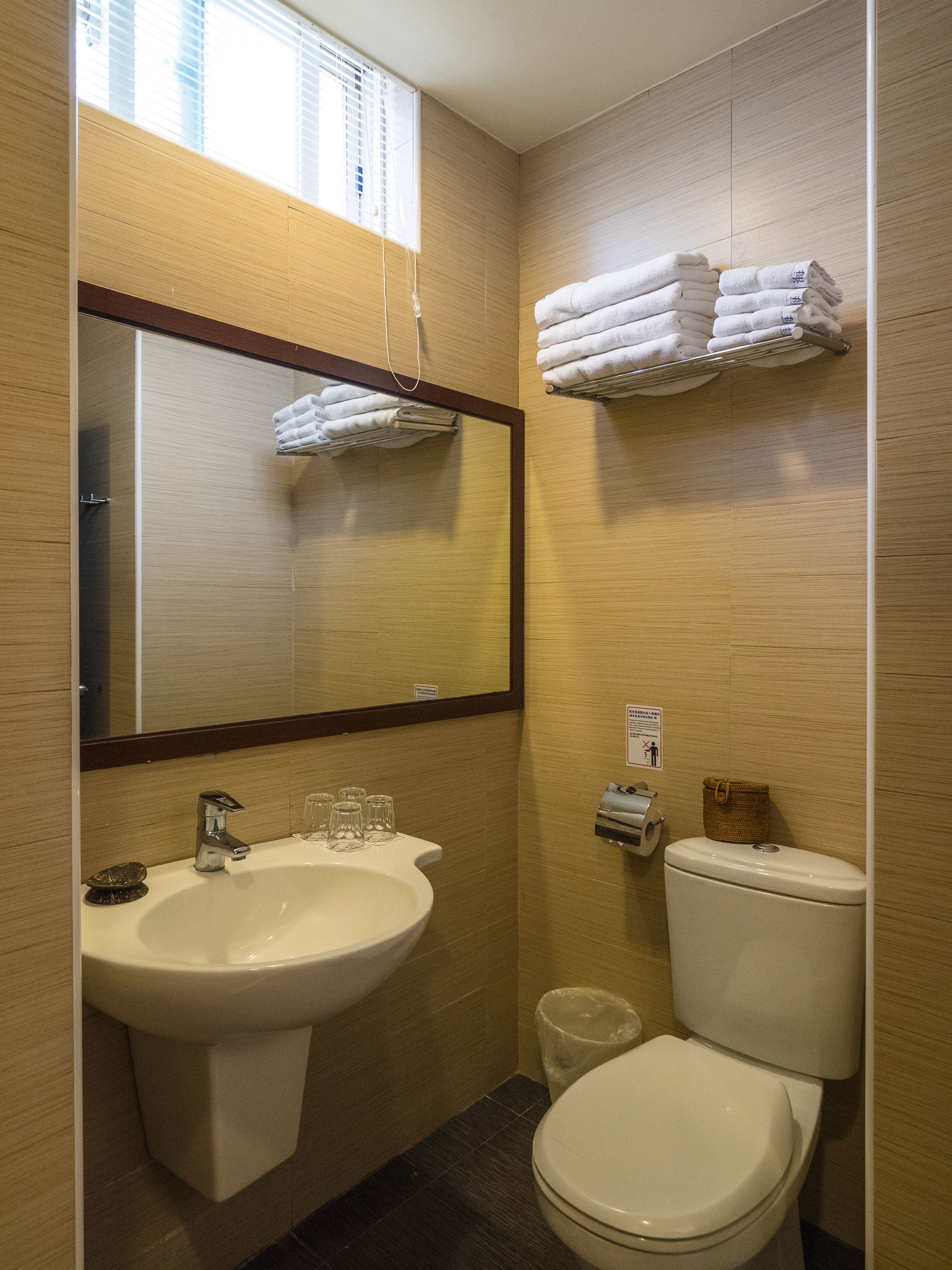 Casa de banho de hotel compacta, com lavatório, espelho e sanita.