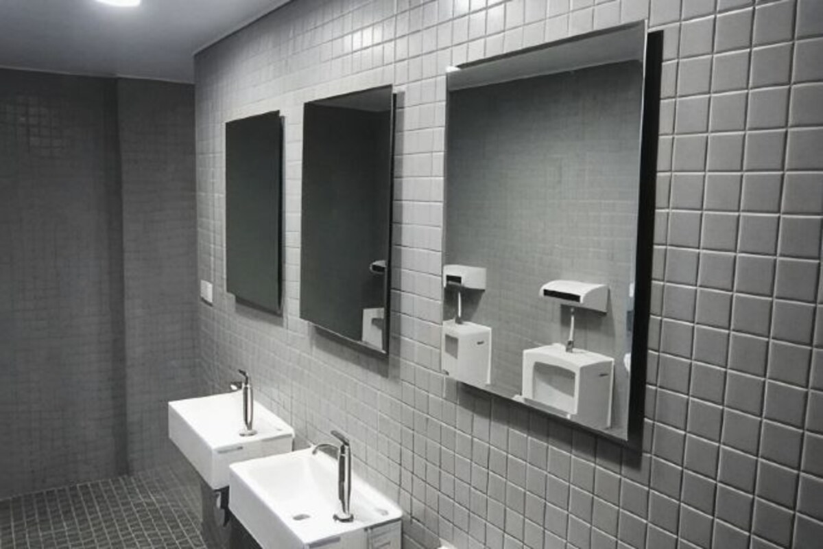 Uma casa de banho moderna com duas lavatórios, espelho e parede revestida a azulejos.
