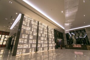 Um lobby moderno com piso espelhado, balcão de recepção e parede estampada.