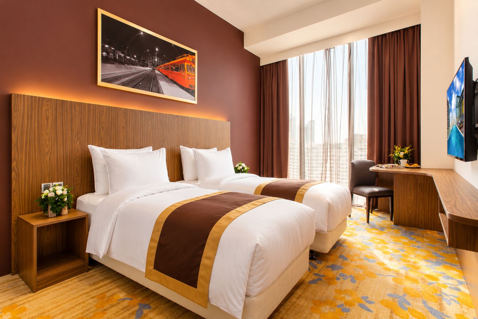 Quarto de hotel com uma cama grande, uma escrivaninha e uma televisão.