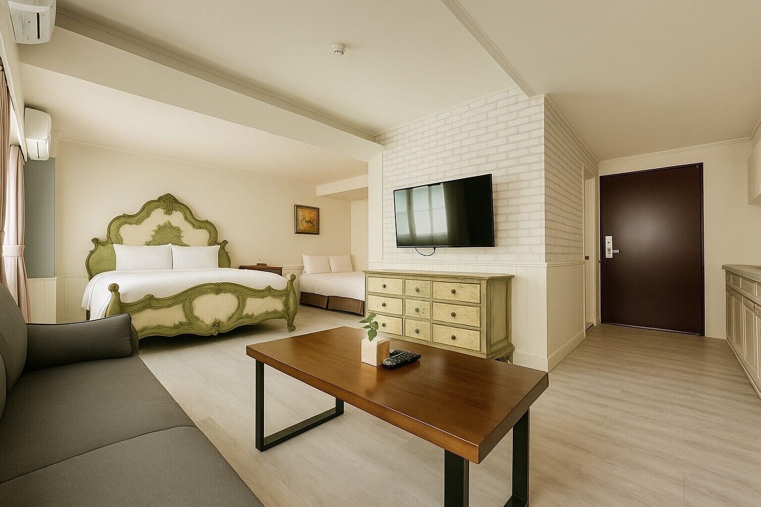 Quarto de hotel com cama, televisão na parede, mesa de madeira e sofá.