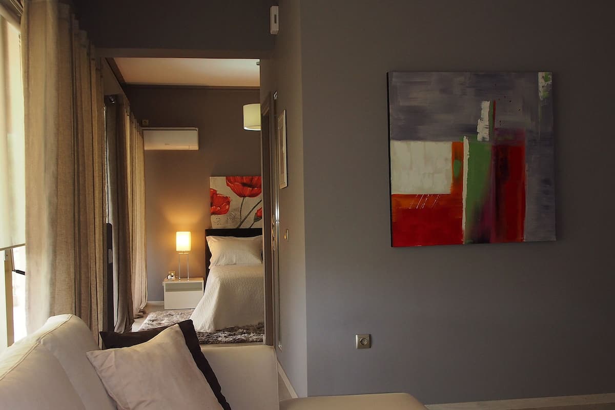 Quarto de hotel moderno com uma cama grande, um sofá e um quadro na parede.