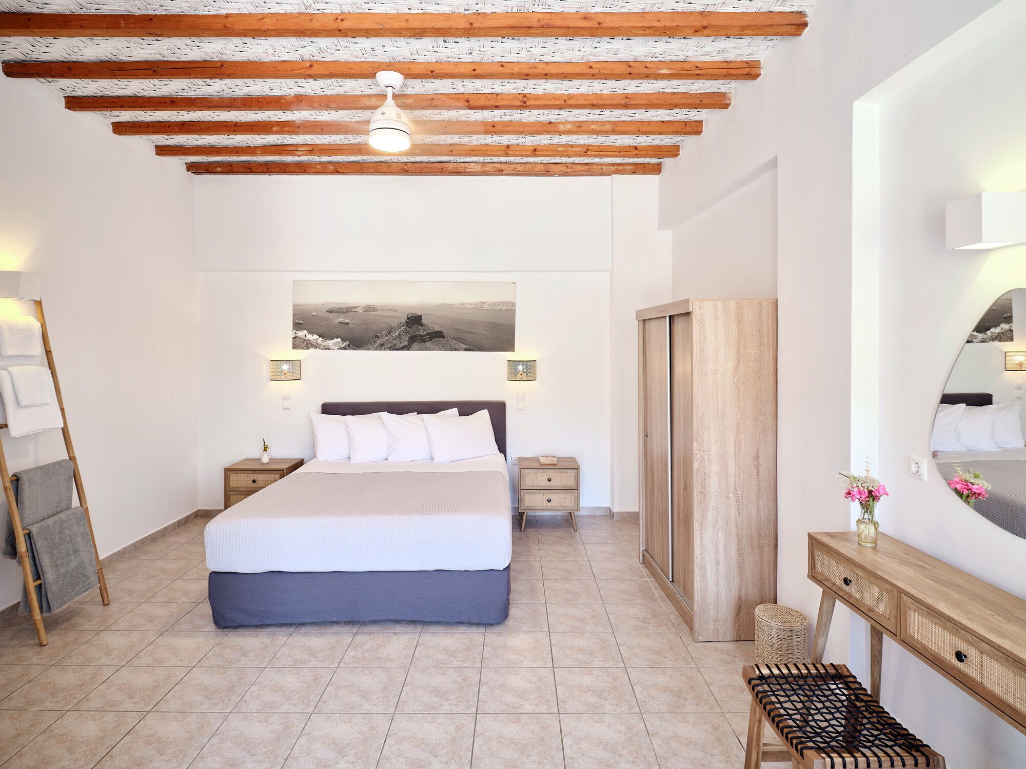 Um quarto com cama, mesas de cabeceira, guarda-roupa, espelho e um quadro na parede.
