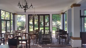 Uma sala de jantar com lustre, janelas amplas e vista para o jardim.