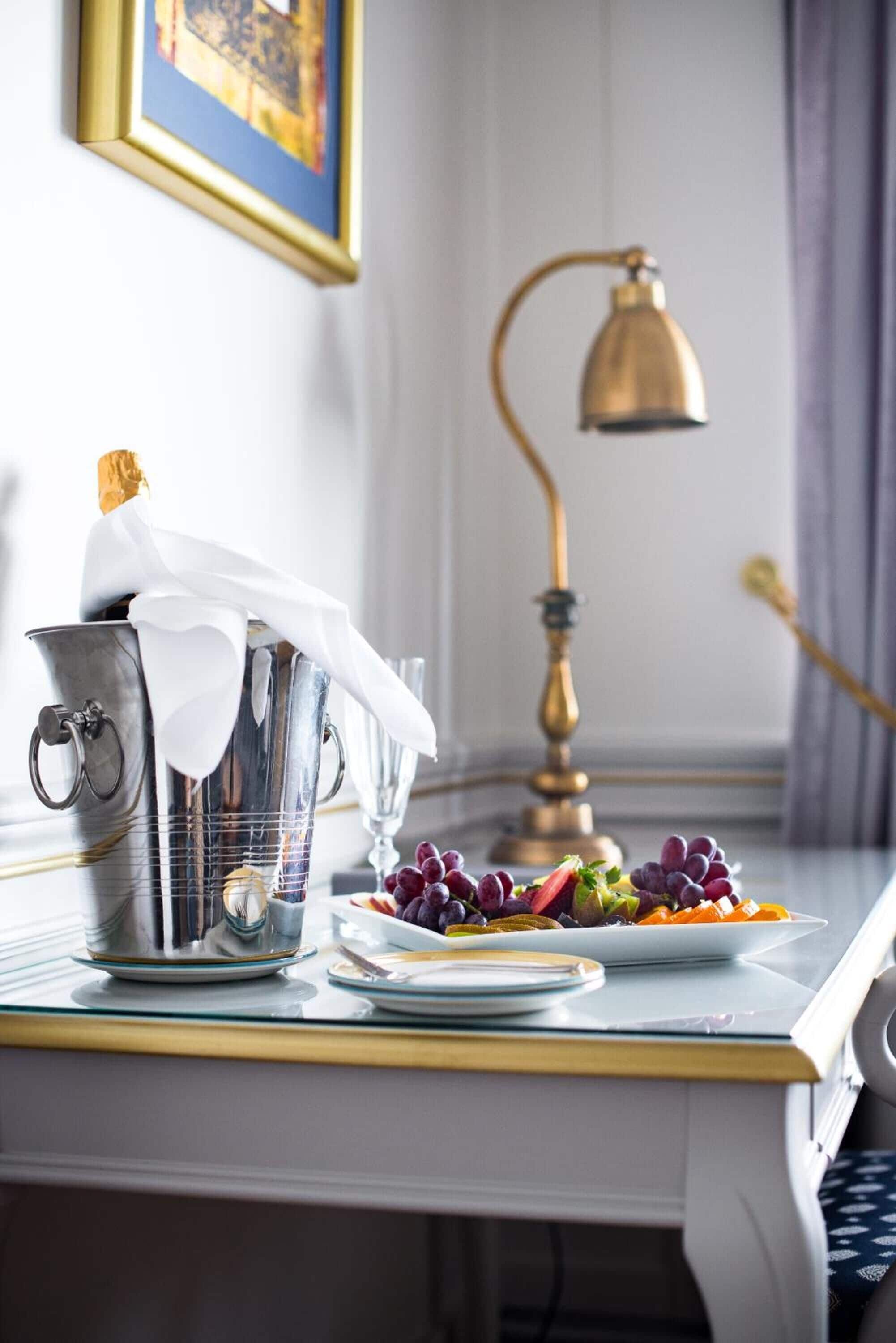 Uma mesa com balde de champanhe, um prato de uvas e um castiçal.