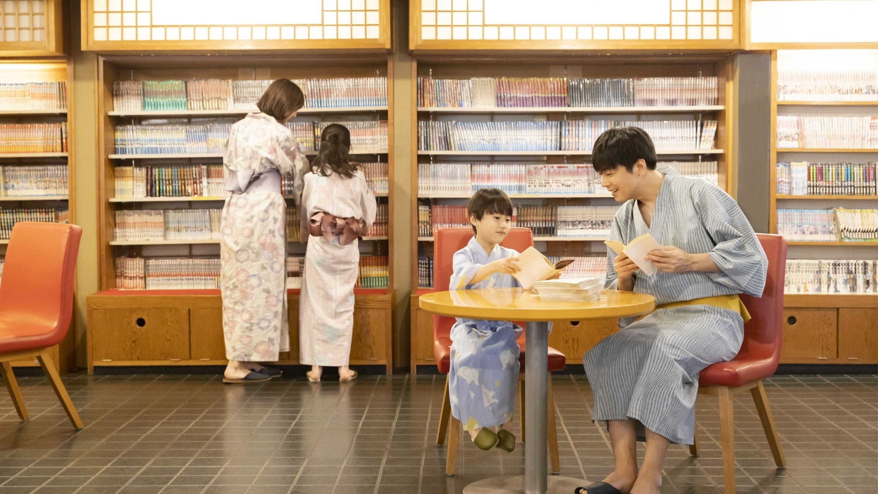 Interior de biblioteca com estantes, uma mesa redonda e cadeiras.