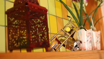 Um dispositivo mecânico com engrenagens e um mostrador, um lanterna vermelha decorativa e um vaso com flores.