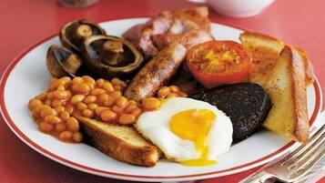 Prato de comida de café da manhã com ovos, salsichas, cogumelos, feijão, tomate e torradas.