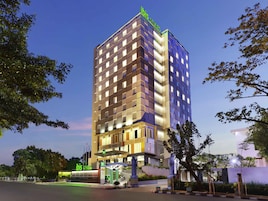 Um hotel de vários andares com design moderno, exibindo uma placa chamativa 'ibis Styles' na entrada.