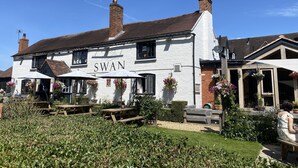 Um pub chamado 'Swan', com mesas ao ar livre e um jardim.
