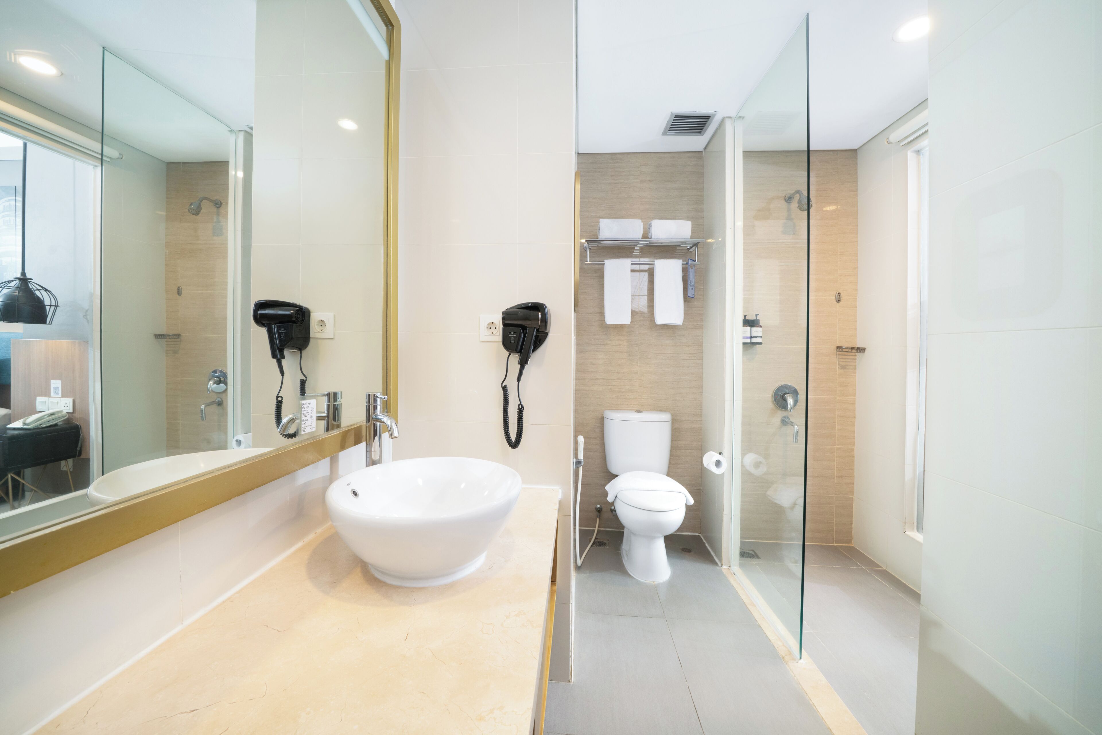 Uma casa de banho moderna com um espelho grande, uma sanita branca, uma casa de wc e uma área de duche com divisória de vidro.