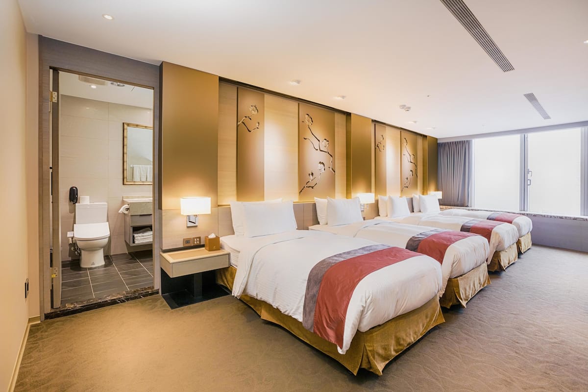 Quarto de hotel com uma cama grande, mesa de cabeceira, espelho e vista para a cidade.