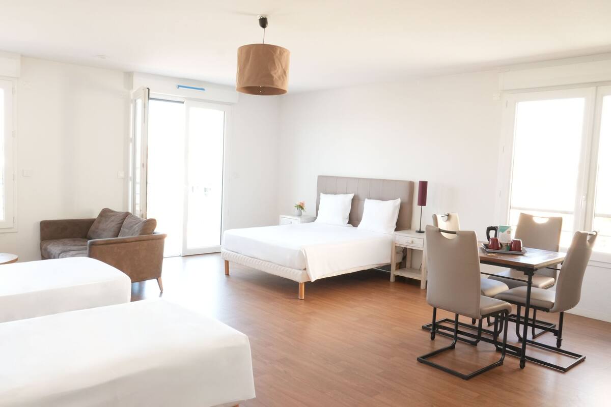 Quarto de hotel moderno com cama, sofá, escrivaninha e cadeira.