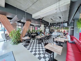 Um café moderno com chão quadriculado, cadeiras listradas em preto e branco e um sofá vermelho.