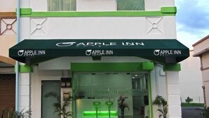 Um hotel chamado Apple Inn, com esquema de cores verde e branco, um número de contato e entrada de vidro.