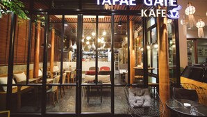 Interior de café com móveis de madeira, luminárias pendentes e um balcão visível.