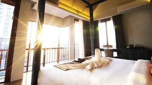 Quarto de hotel com uma cama grande, uma mesa e vista para o exterior.