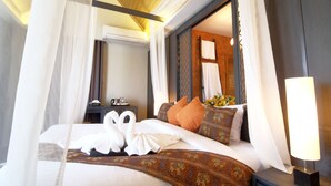 Cama bem arrumada com lençóis brancos e cisnes decorativos, mesa de cabeceira com abajur, e vista de um quarto com teto de madeira e janela com cortinas.