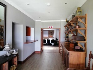 Um corredor com um armário de madeira à direita, um espelho à esquerda e uma porta que dá para uma sala de jantar.