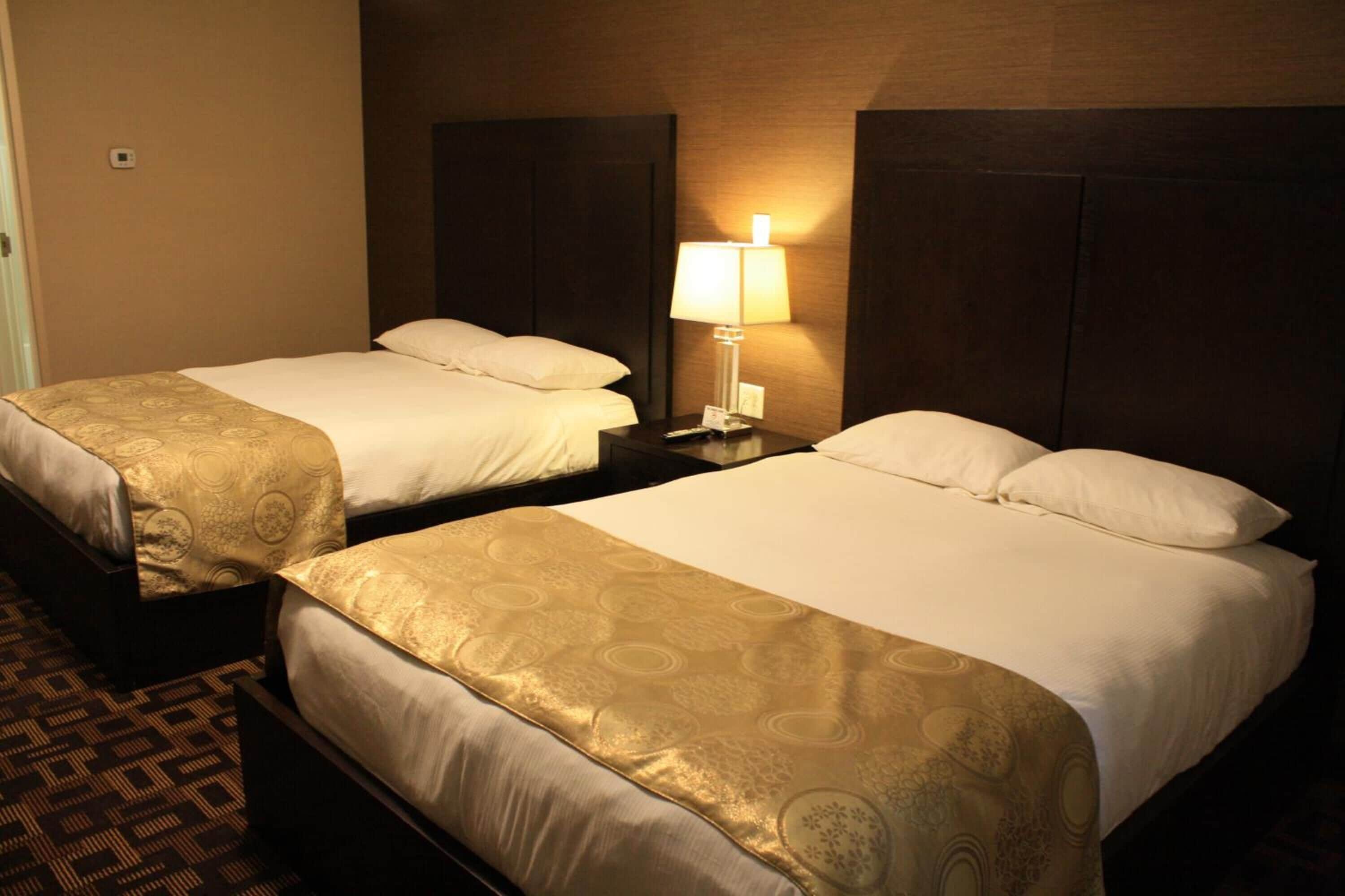 Duas camas de solteiro com colchas estampadas em dourado em um quarto de hotel.