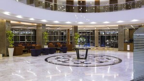 Um hall amplo com área de estar central, vários níveis com guarda-corpos de vidro e design moderno.