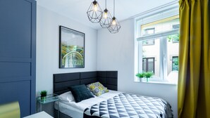 Quarto moderno com cama, mesa de cabeceira e janela com cortinas.