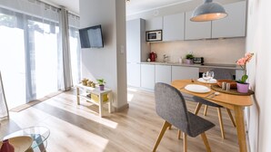 Cozinha moderna com área de jantar, piso de madeira e TV fixada na parede.