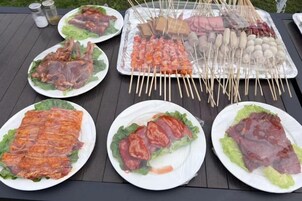 Uma mesa com diversos alimentos, incluindo espetinhos e carnes enroladas, provavelmente preparada para um churrasco.