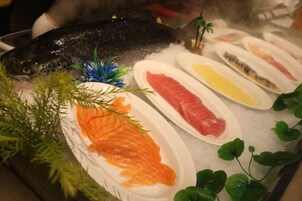 Diversos frutos do mar frescos sobre gelo, incluindo salmão e outros peixes, com folhagem decorativa.