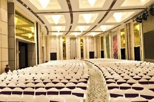 Um amplo auditório circular com fileiras de cadeiras brancas e um corredor central.