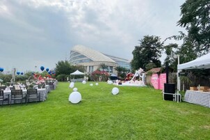 Espaço para eventos ao ar livre com uma tenda, mesas e cadeiras dispostas numa área gramada.