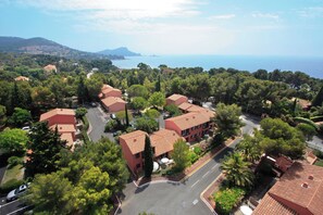 Um bairro residencial com edifícios de telhado vermelho, árvores verdes e vista para o mar.